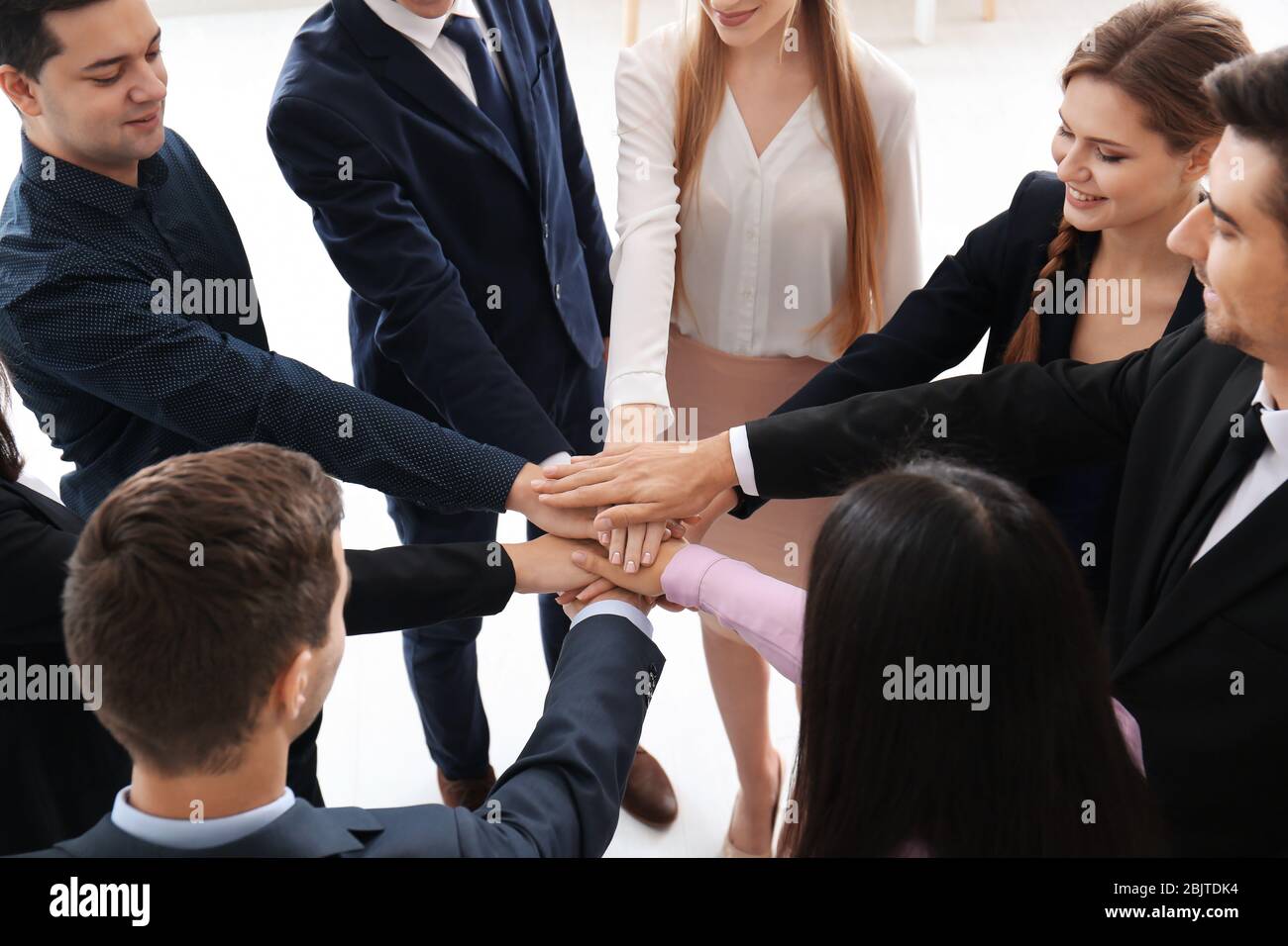 People putting hands together indoors. Unity concept Stock Photo - Alamy