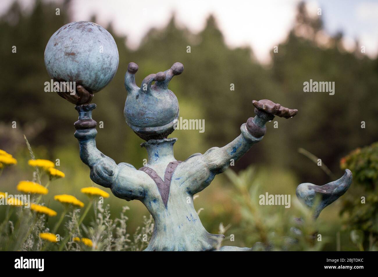 A playful statue, holding a ball, dances through a field of yellow ...