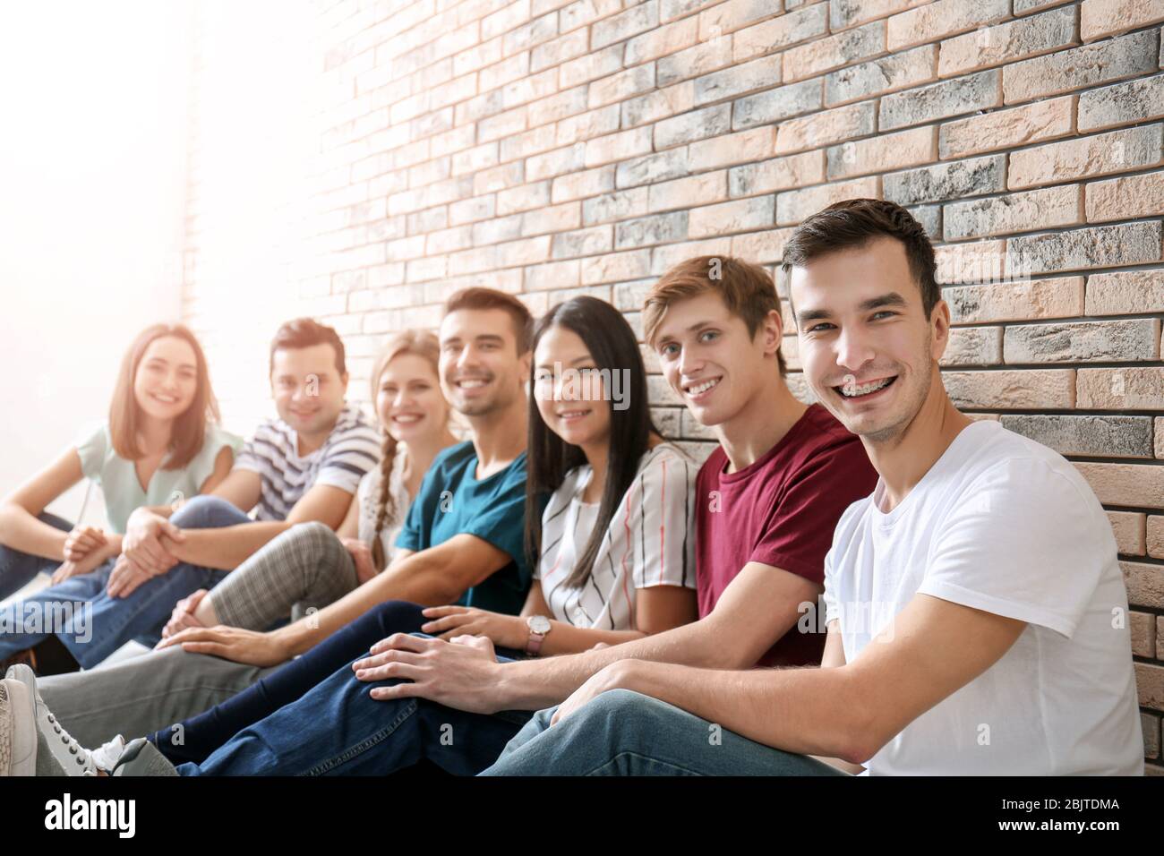 People sitting together near brick wall. Unity concept Stock Photo - Alamy