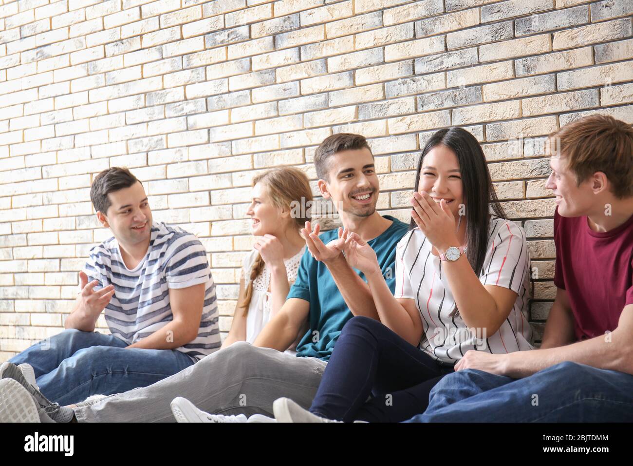 People sitting together near brick wall. Unity concept Stock Photo - Alamy