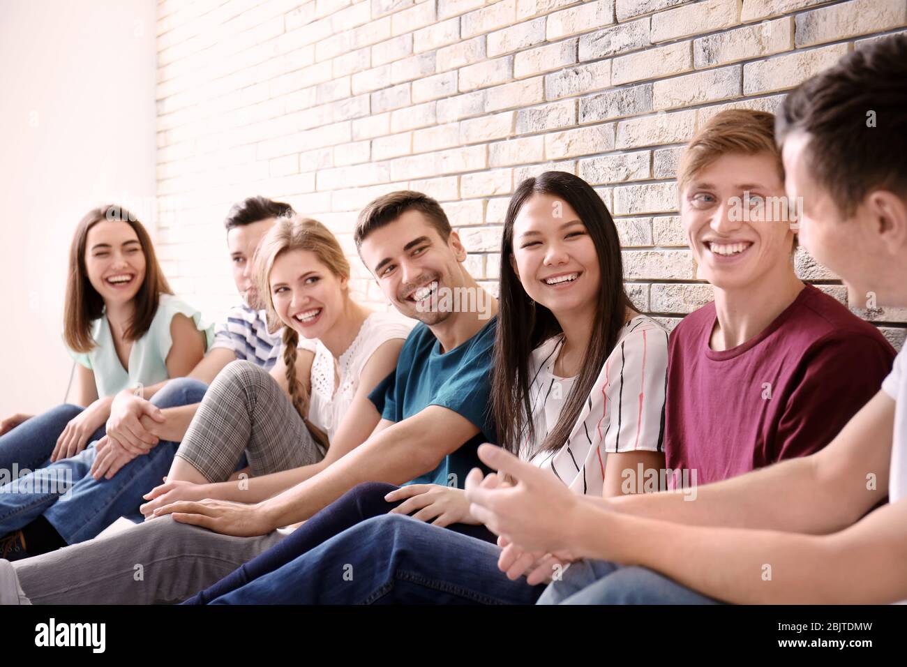 People sitting together near brick wall. Unity concept Stock Photo - Alamy
