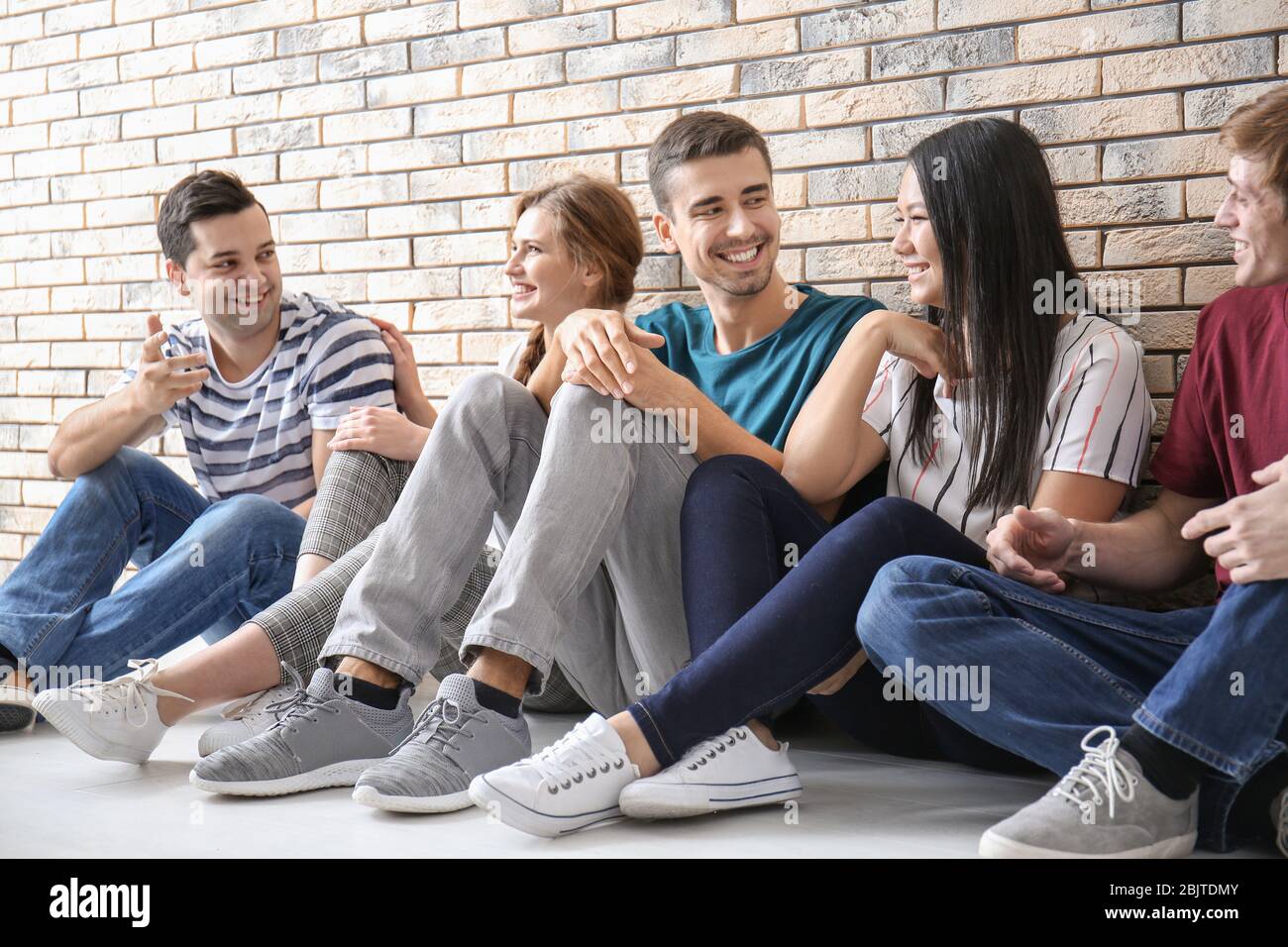 People sitting together near brick wall. Unity concept Stock Photo - Alamy