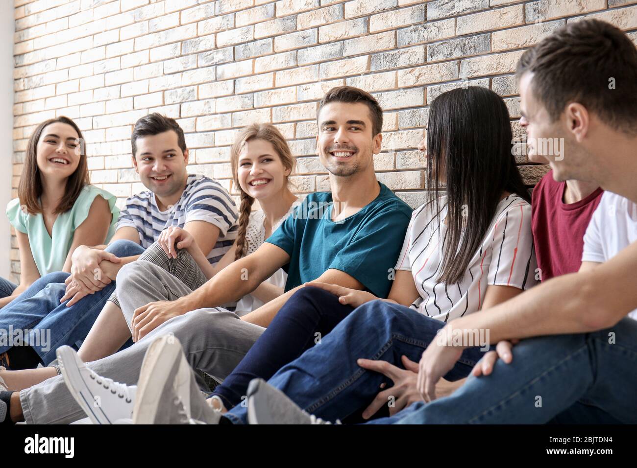 People sitting together near brick wall. Unity concept Stock Photo - Alamy