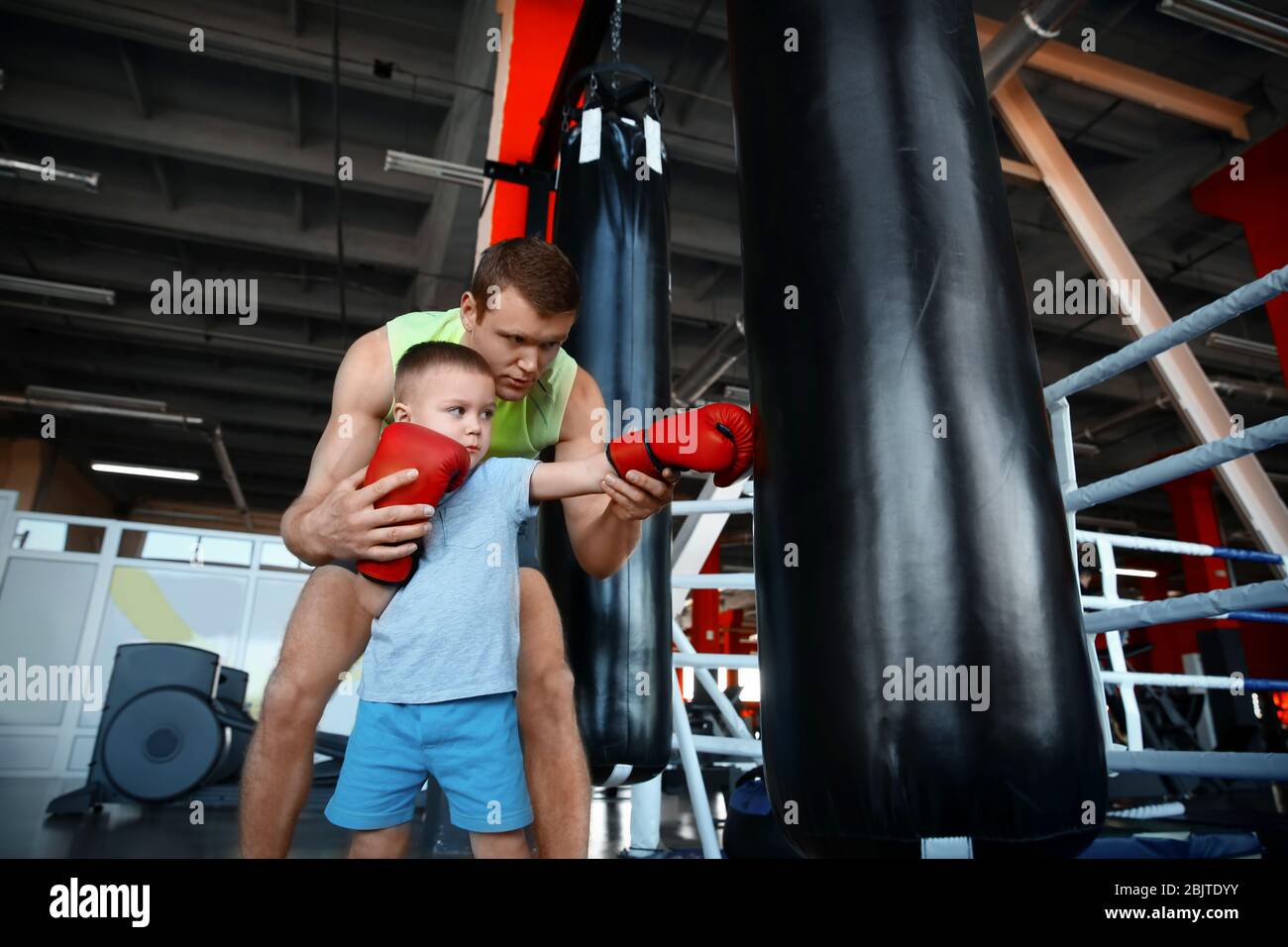 Little boy training with coach and punchbag in boxing gym Stock Photo ...