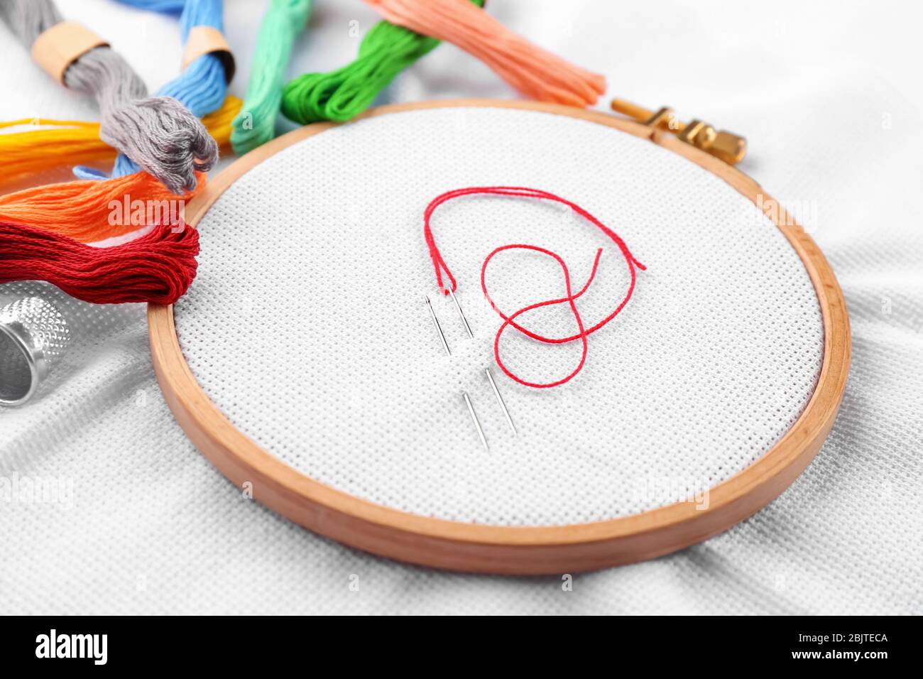 Embroidery hoop with fabric, sewing needles and thread, closeup Stock ...