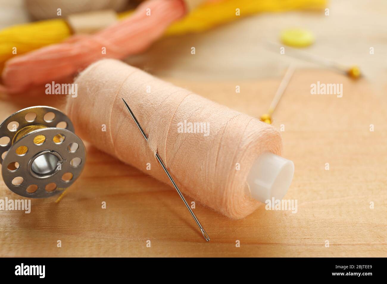 Spool of sewing thread with needle on table Stock Photo - Alamy