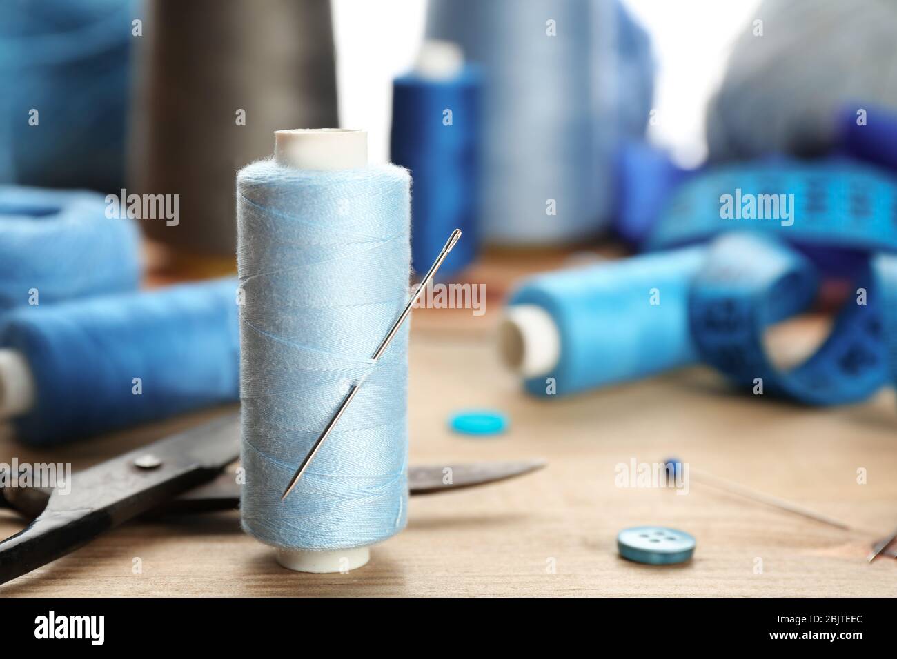 Spool of sewing thread with needle on table Stock Photo - Alamy