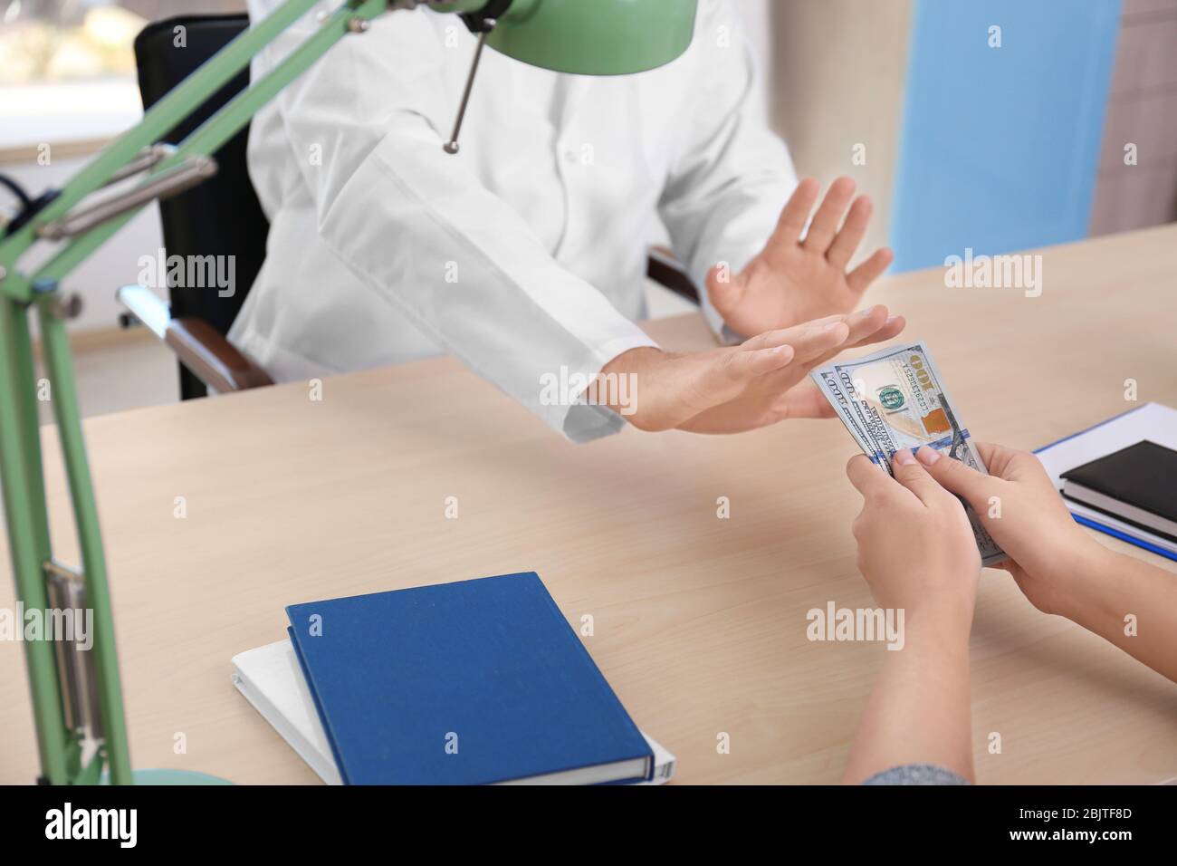 Male doctor refusing to take bribe from woman at workplace Stock Photo ...