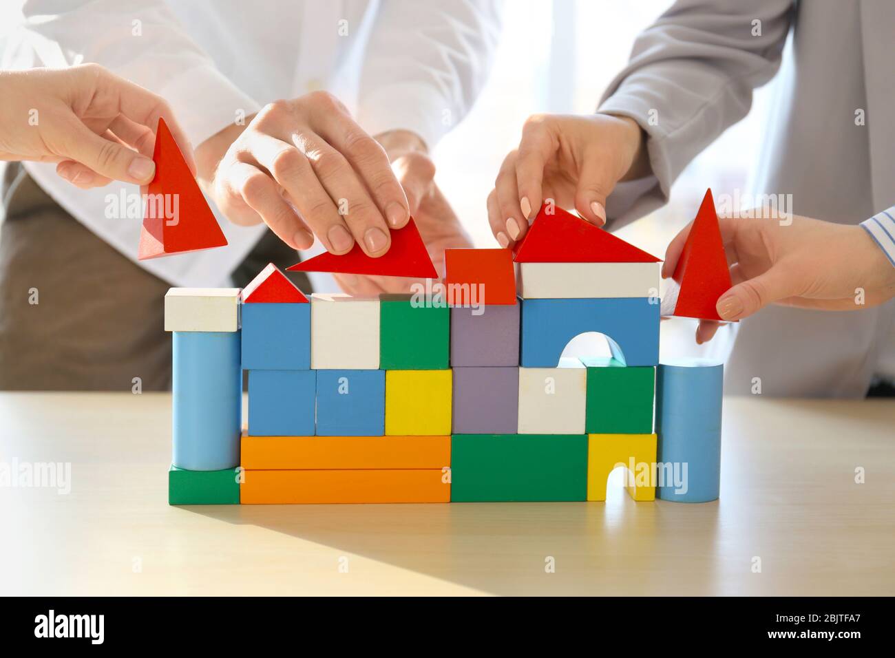 People building house together on table, closeup. Unity concept Stock ...