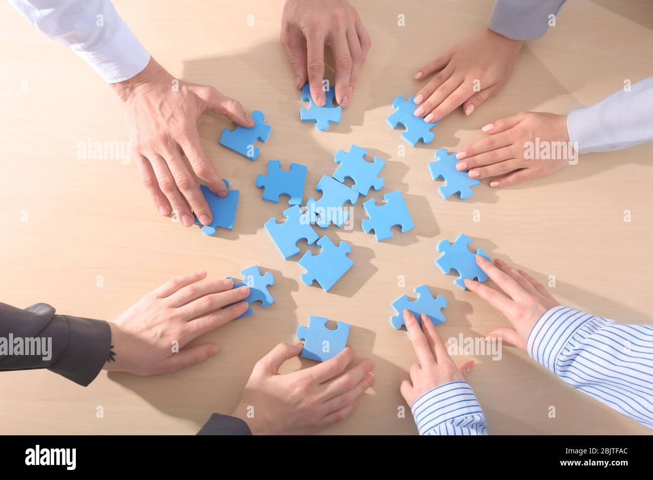People solving puzzle together on table, top view. Unity concept Stock ...