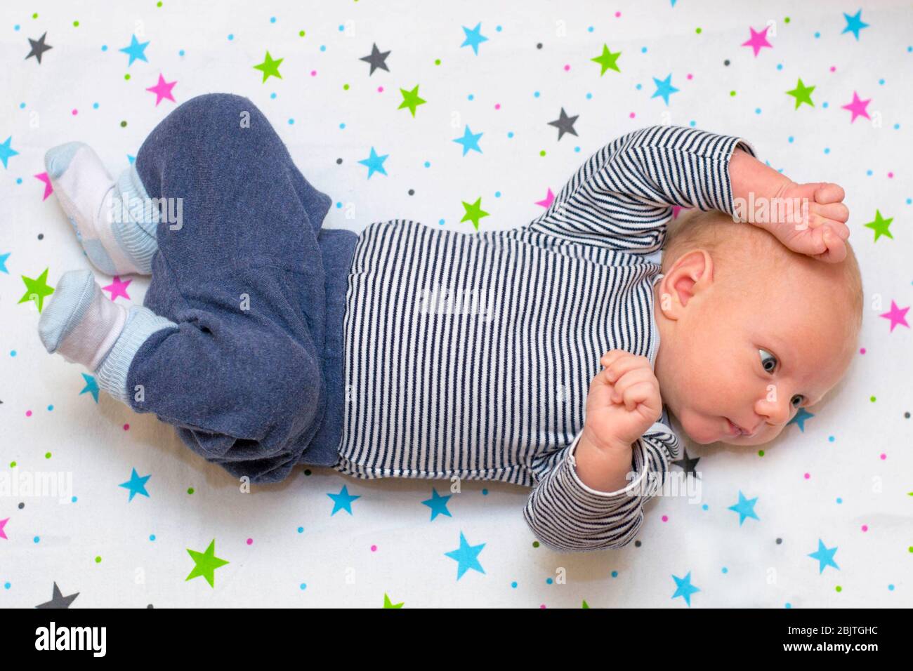 Portrait of a cute newborn baby who lies on his back in a crib, top ...