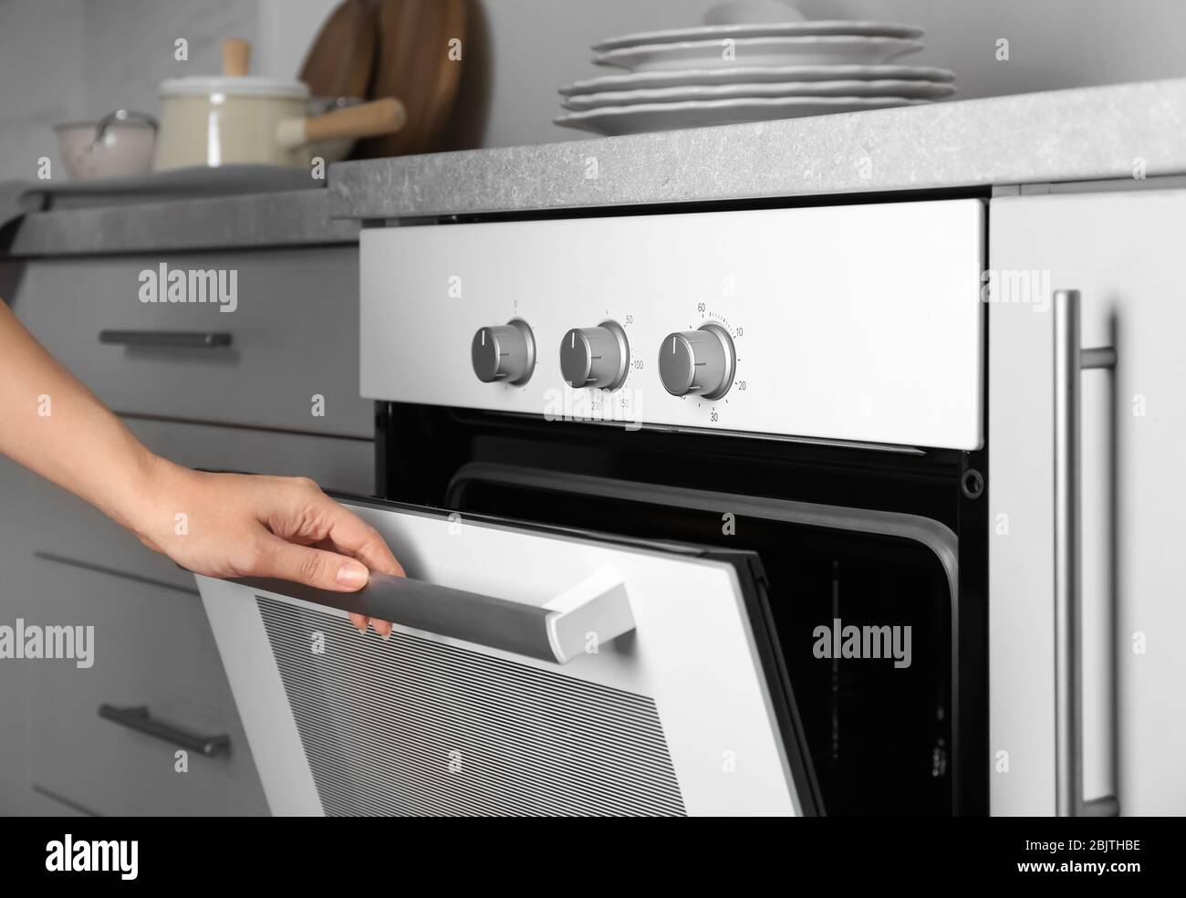 Young woman opening modern electrical oven in kitchen Stock Photo - Alamy