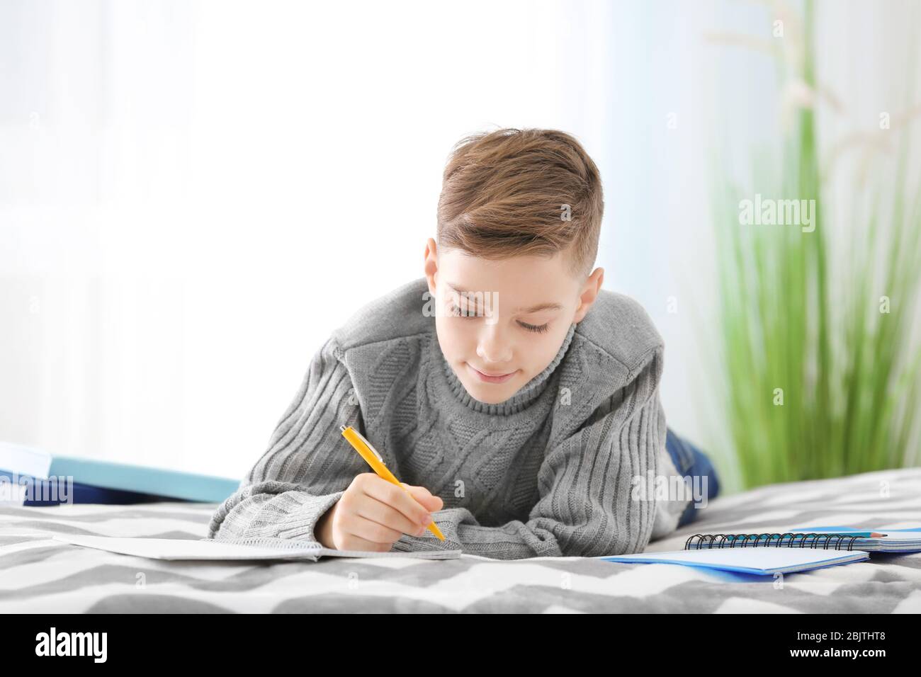 Cute teenager doing homework on bed Stock Photo - Alamy