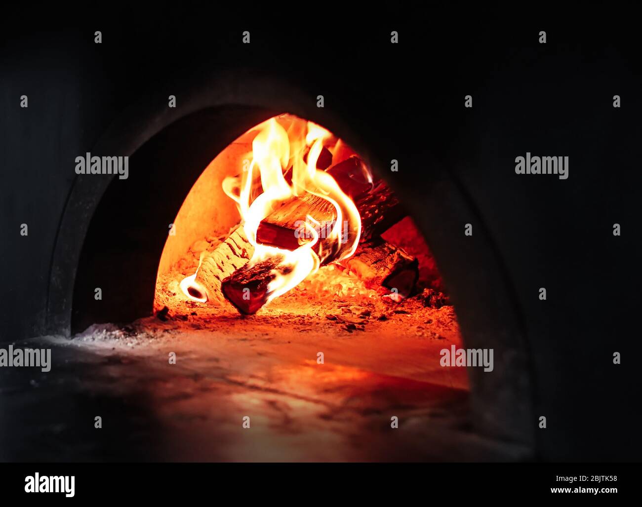 Burning firewood in traditional oven at restaurant kitchen Stock Photo ...