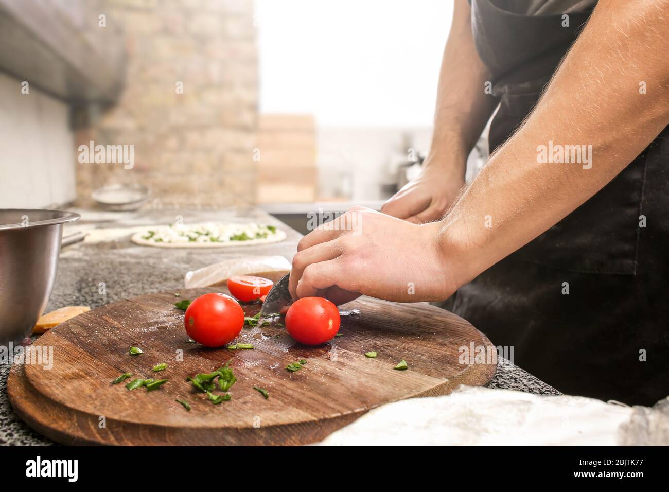 Chef preparing topping for pizza at table in restaurant kitchen Stock ...