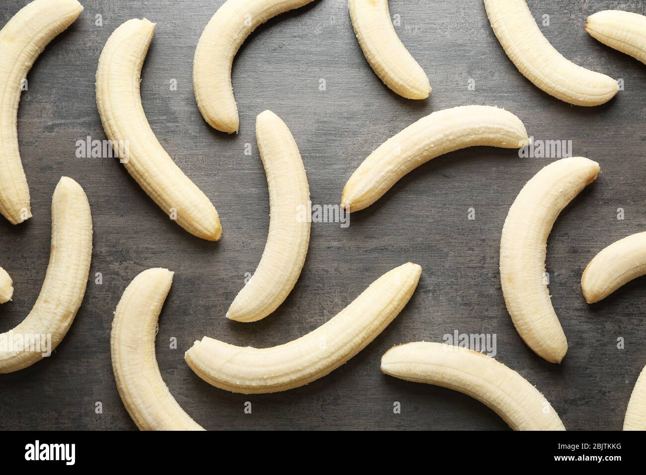 Composition with peeled bananas on grey background Stock Photo - Alamy
