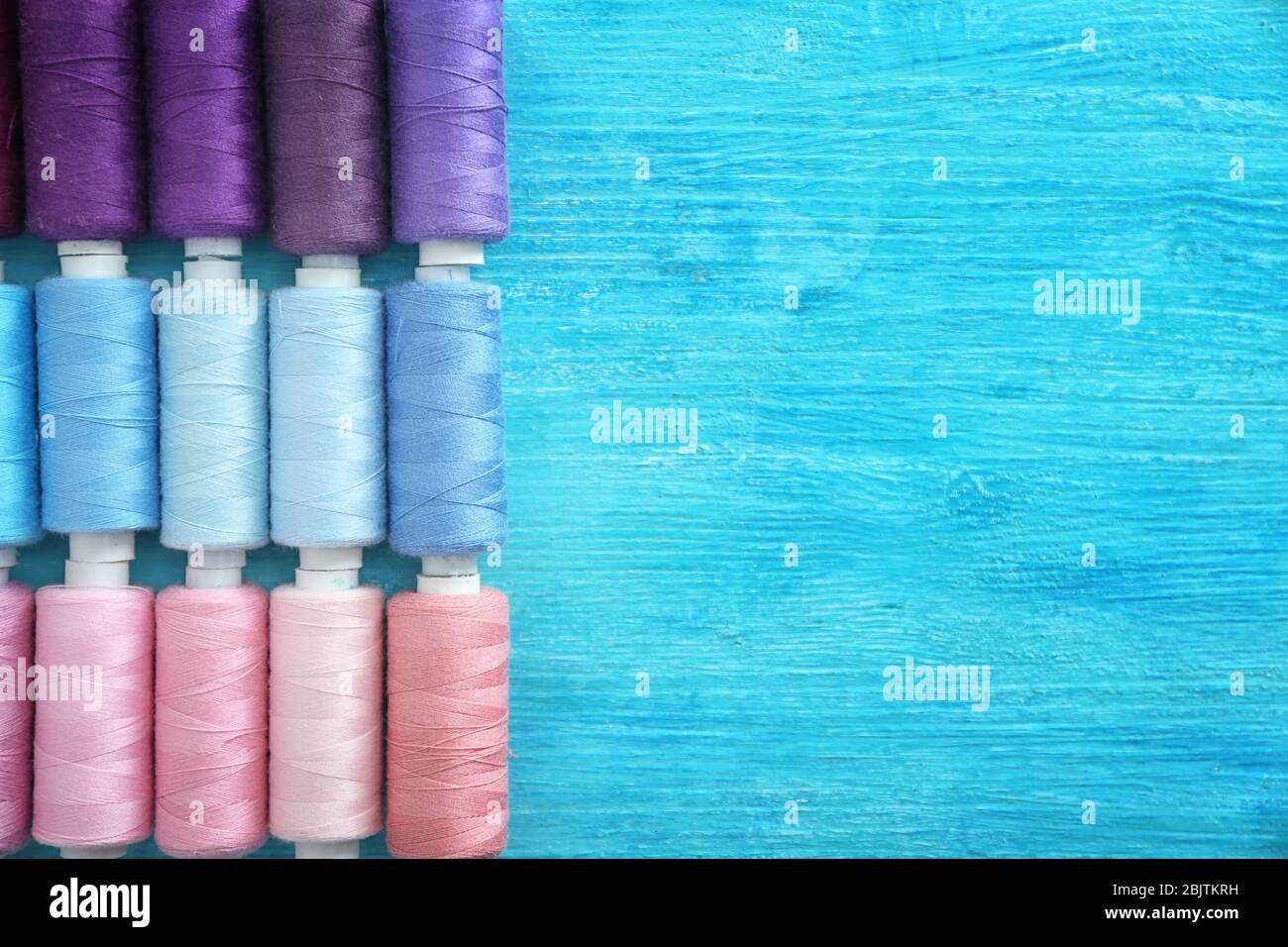 Set of color sewing threads on wooden background Stock Photo - Alamy