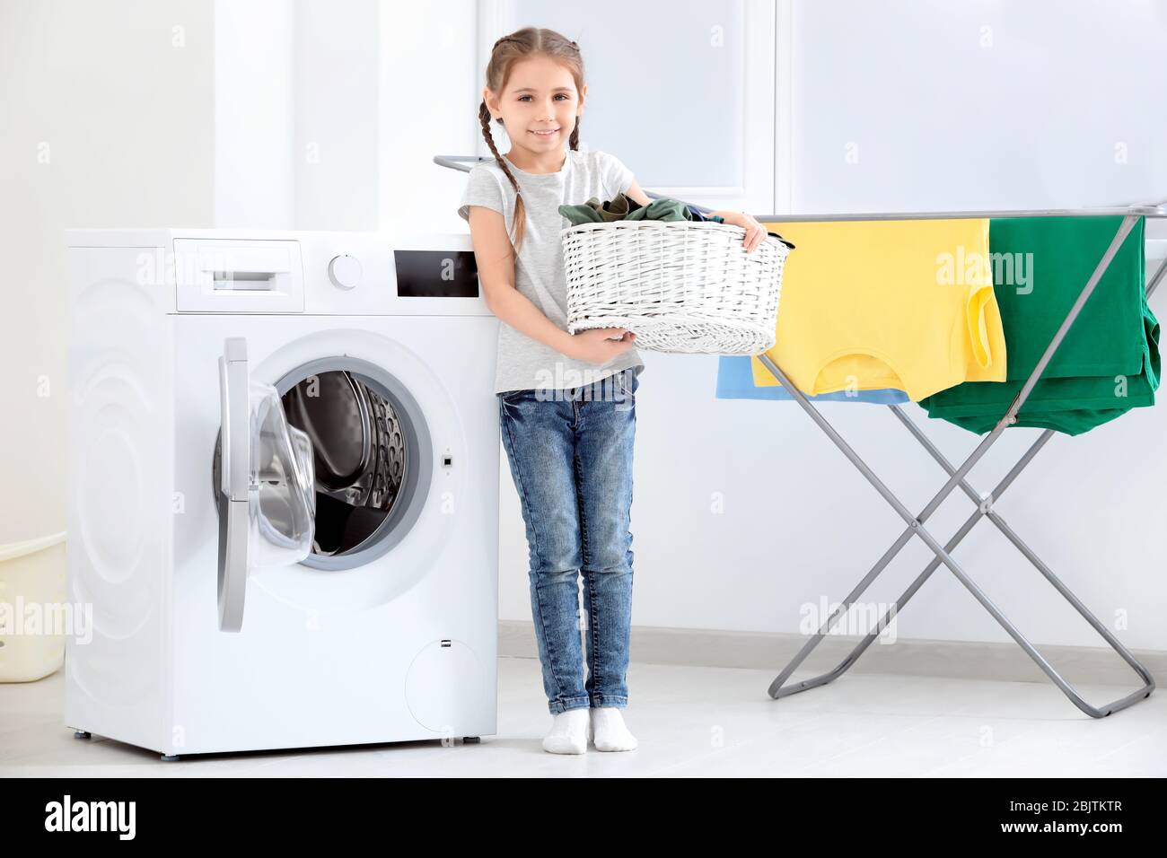 Cute little girl doing laundry at home Stock Photo - Alamy