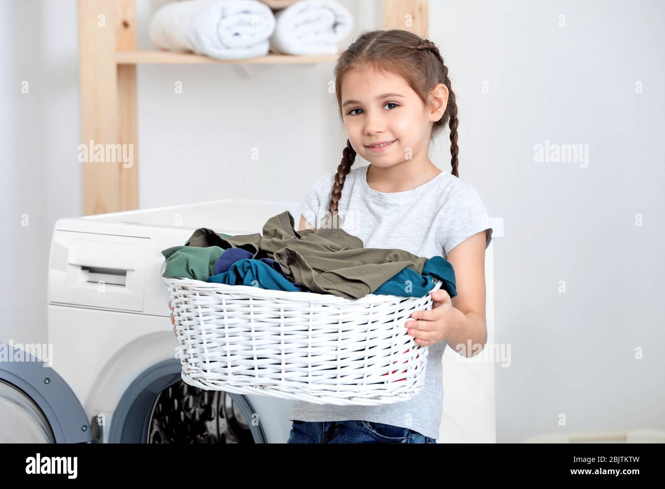 Cute little girl doing laundry at home Stock Photo - Alamy