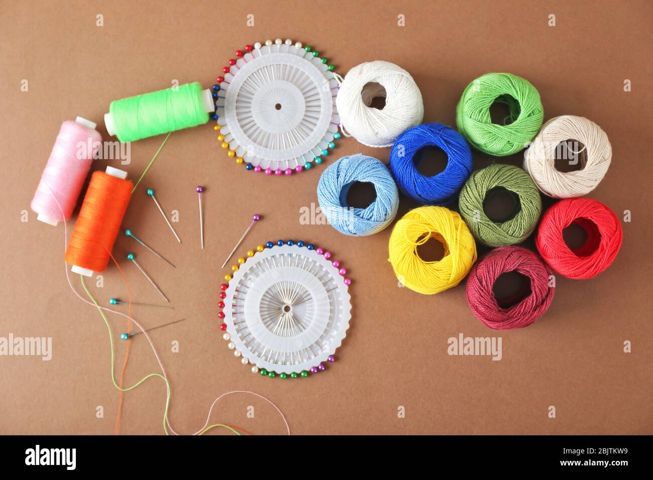 Sewing threads and crocheting clews with pins on color background, top ...