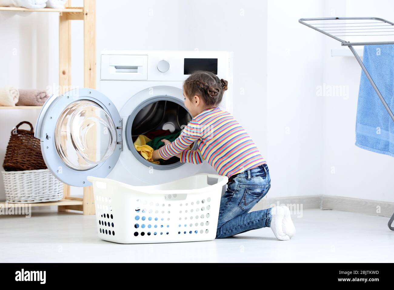 Cute little girl doing laundry at home Stock Photo - Alamy