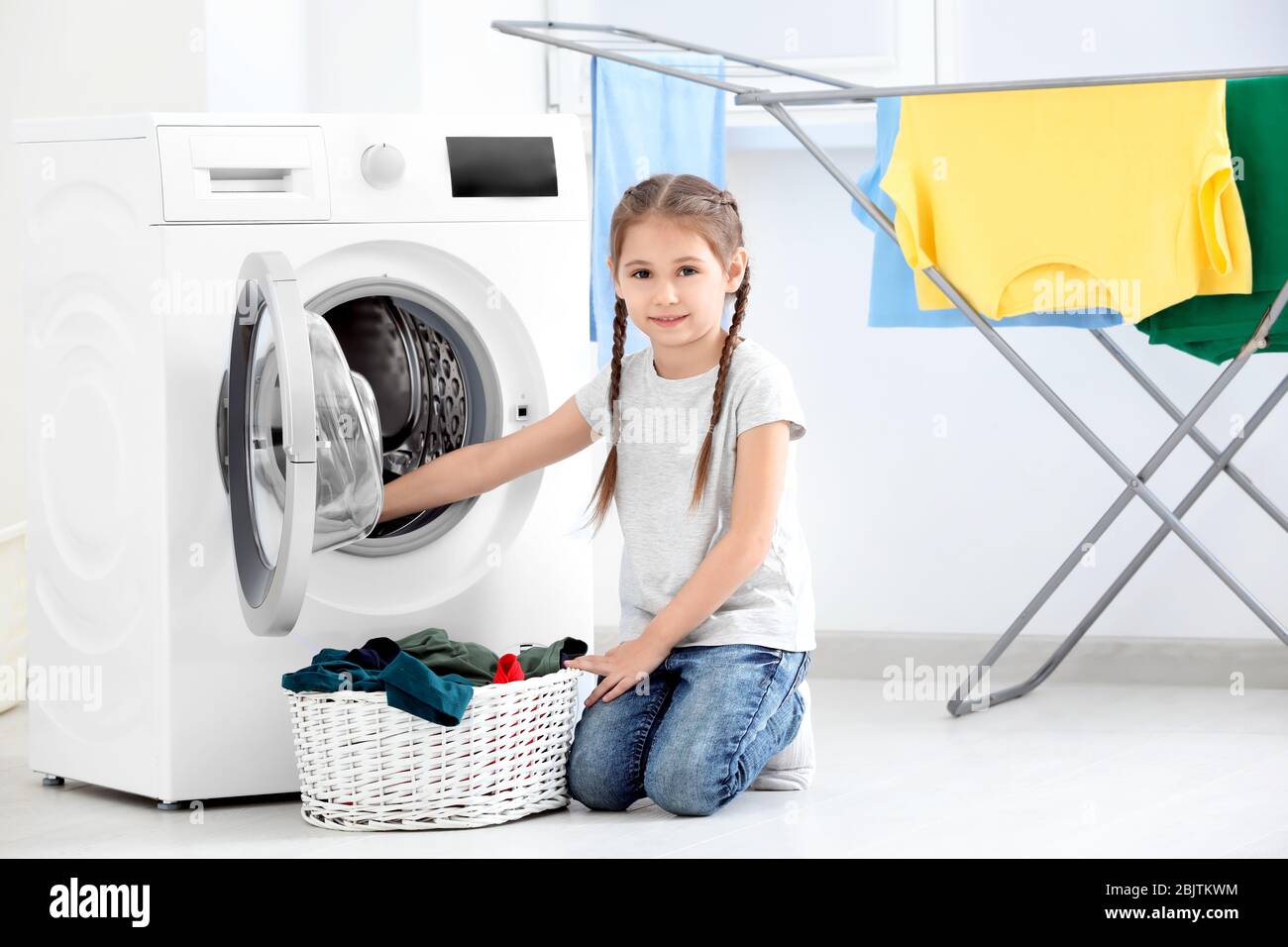 Cute little girl doing laundry at home Stock Photo - Alamy