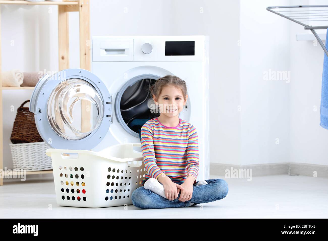 Cute little girl doing laundry at home Stock Photo - Alamy
