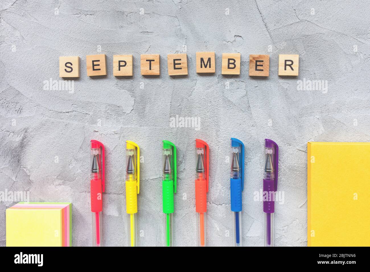 Word SEPTEMBER and multicolored gel pens on a gray background ...