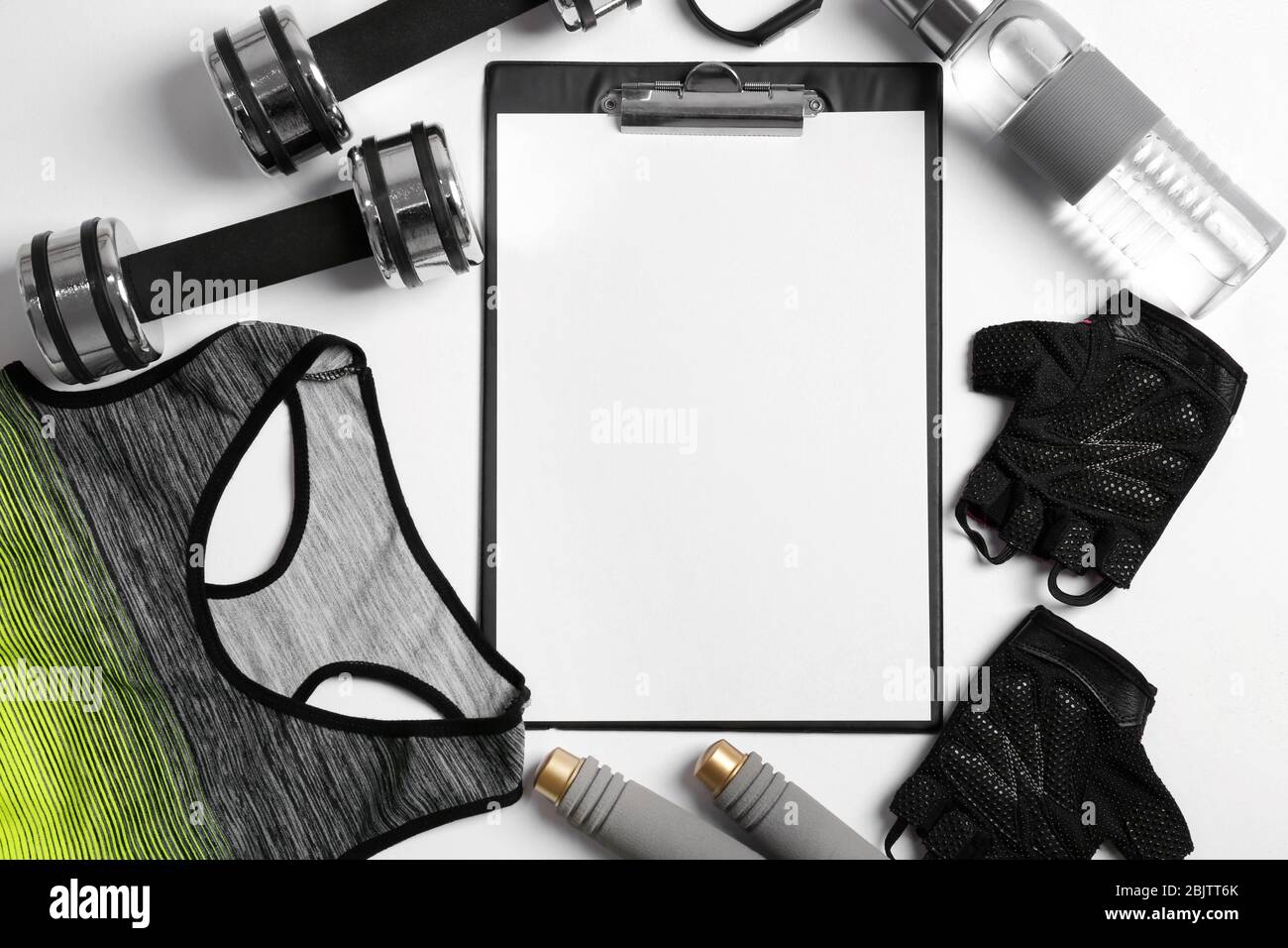 Clipboard with blank paper for exercise plan and gym stuff on white ...