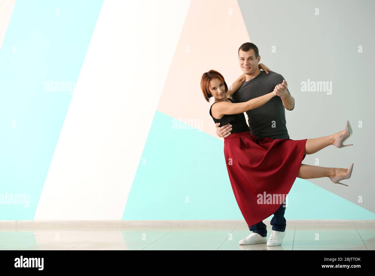 Cute loving couple dancing against color wall Stock Photo - Alamy