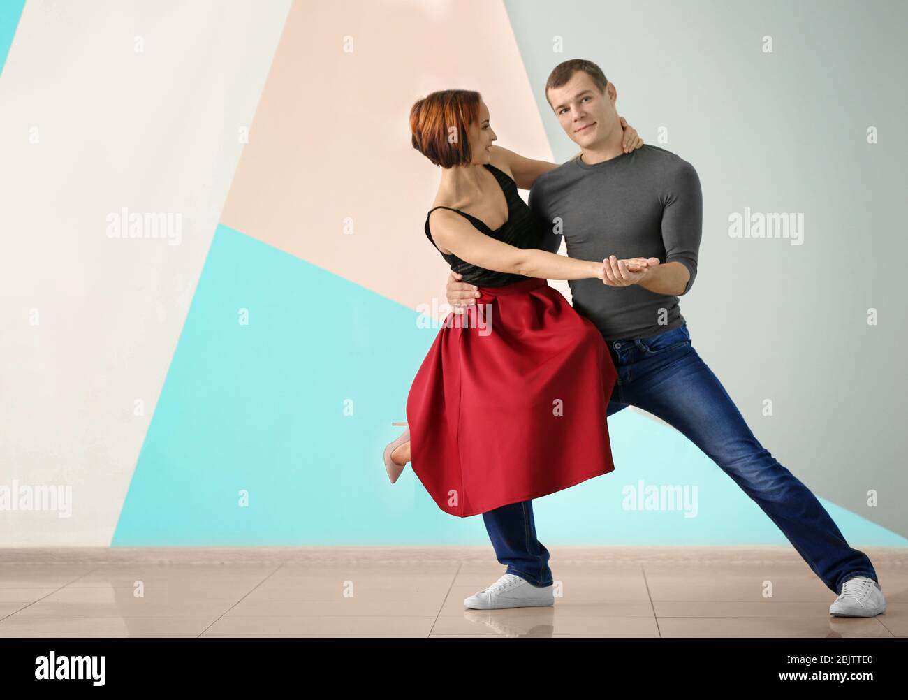 Cute loving couple dancing against color wall Stock Photo - Alamy