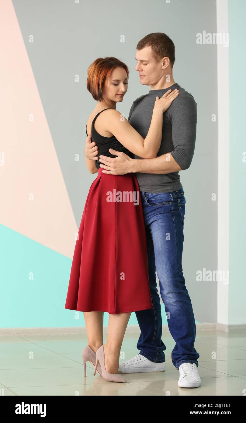 Cute loving couple dancing against color wall Stock Photo - Alamy
