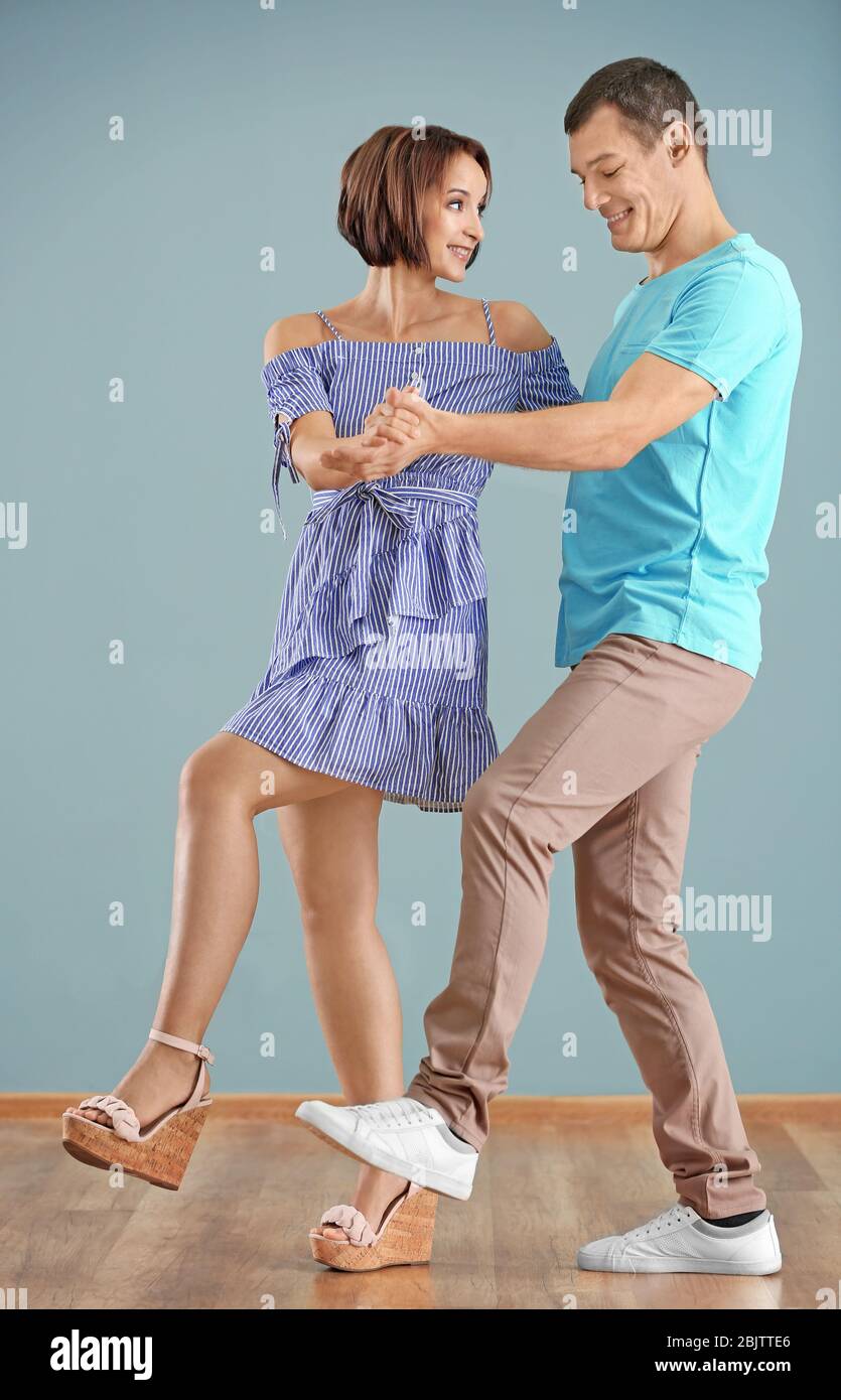 Cute loving couple dancing against color wall Stock Photo - Alamy