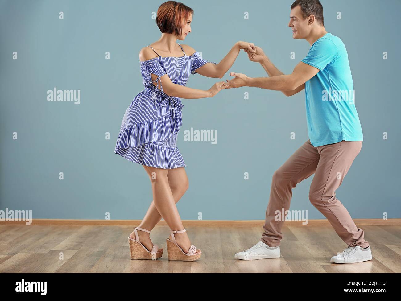 Cute loving couple dancing against color wall Stock Photo - Alamy