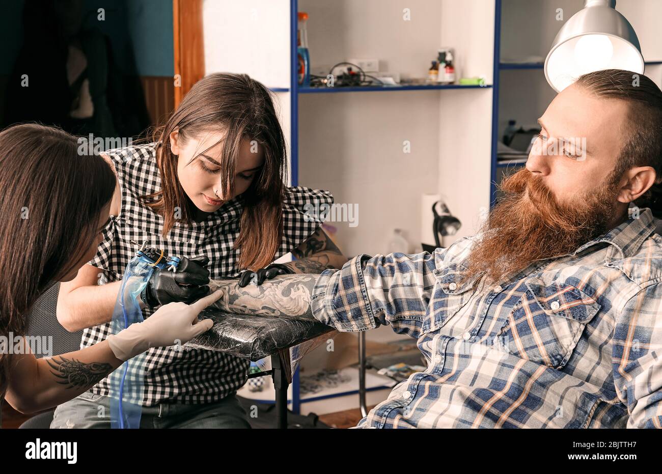 Professional tattoo artist teaching trainee in salon. Apprenticeship ...