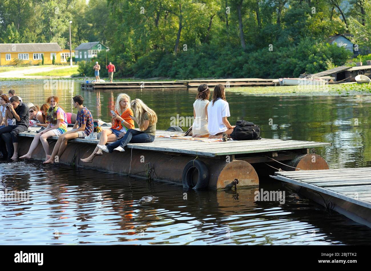 People sitting on the pontoon on the river beach and relaxing under sun ...