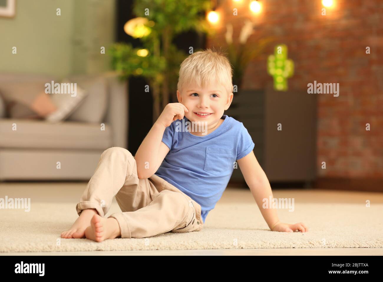 Cute little boy sitting on floor at home Stock Photo - Alamy