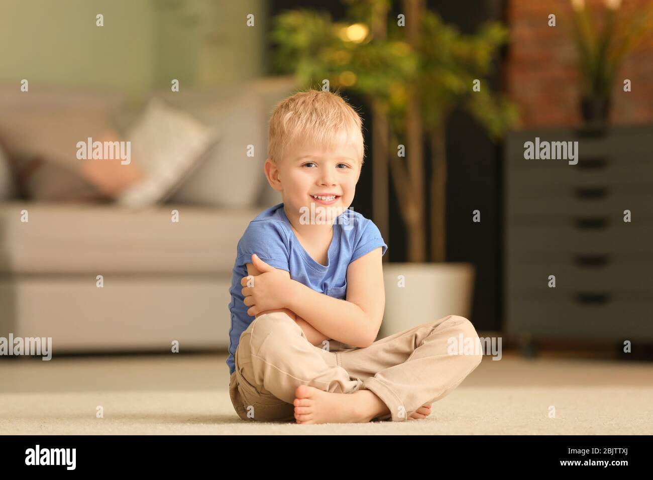 Cute little boy sitting on floor at home Stock Photo - Alamy