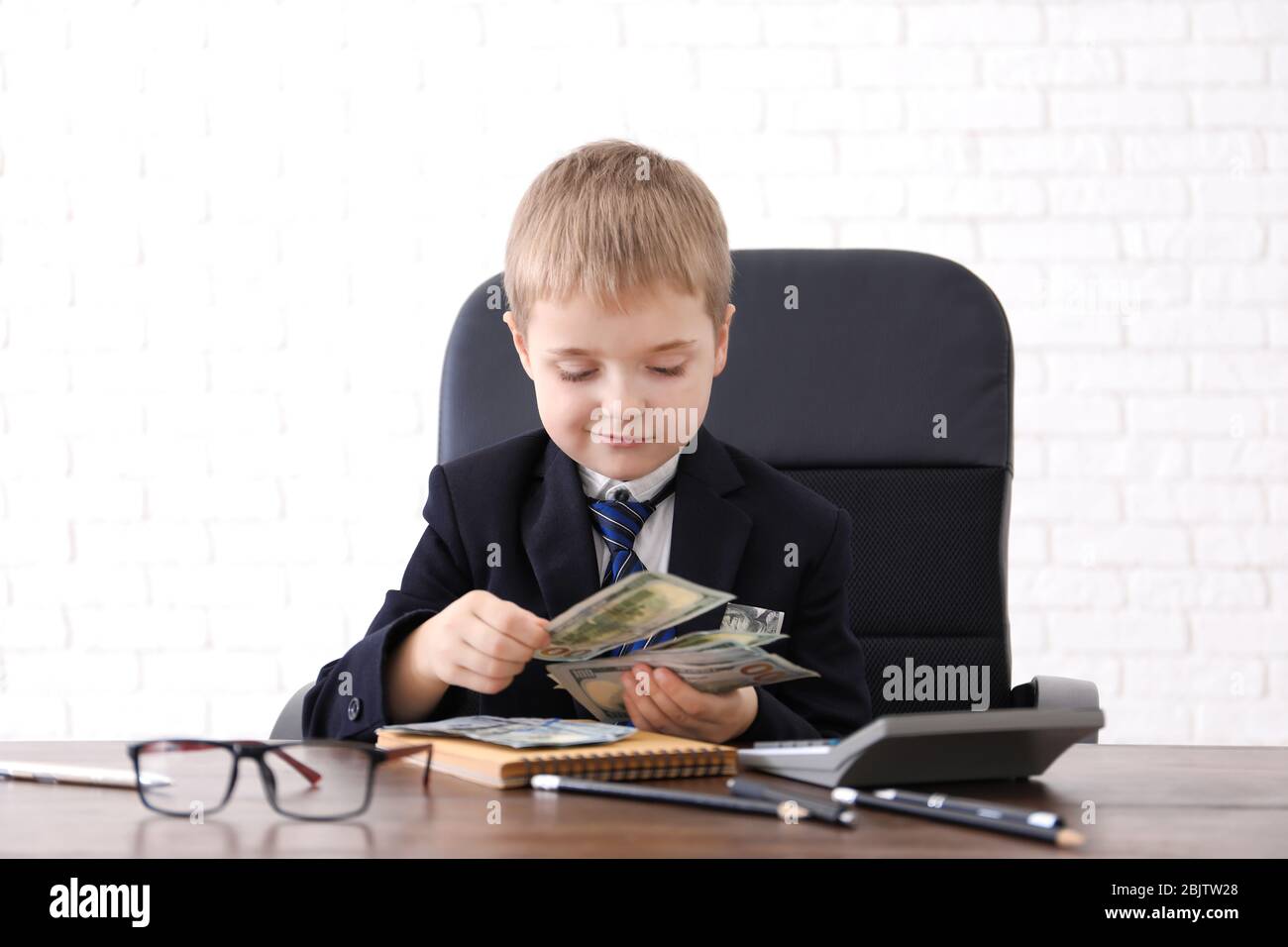 Cute little boy counting money at table indoors Stock Photo - Alamy