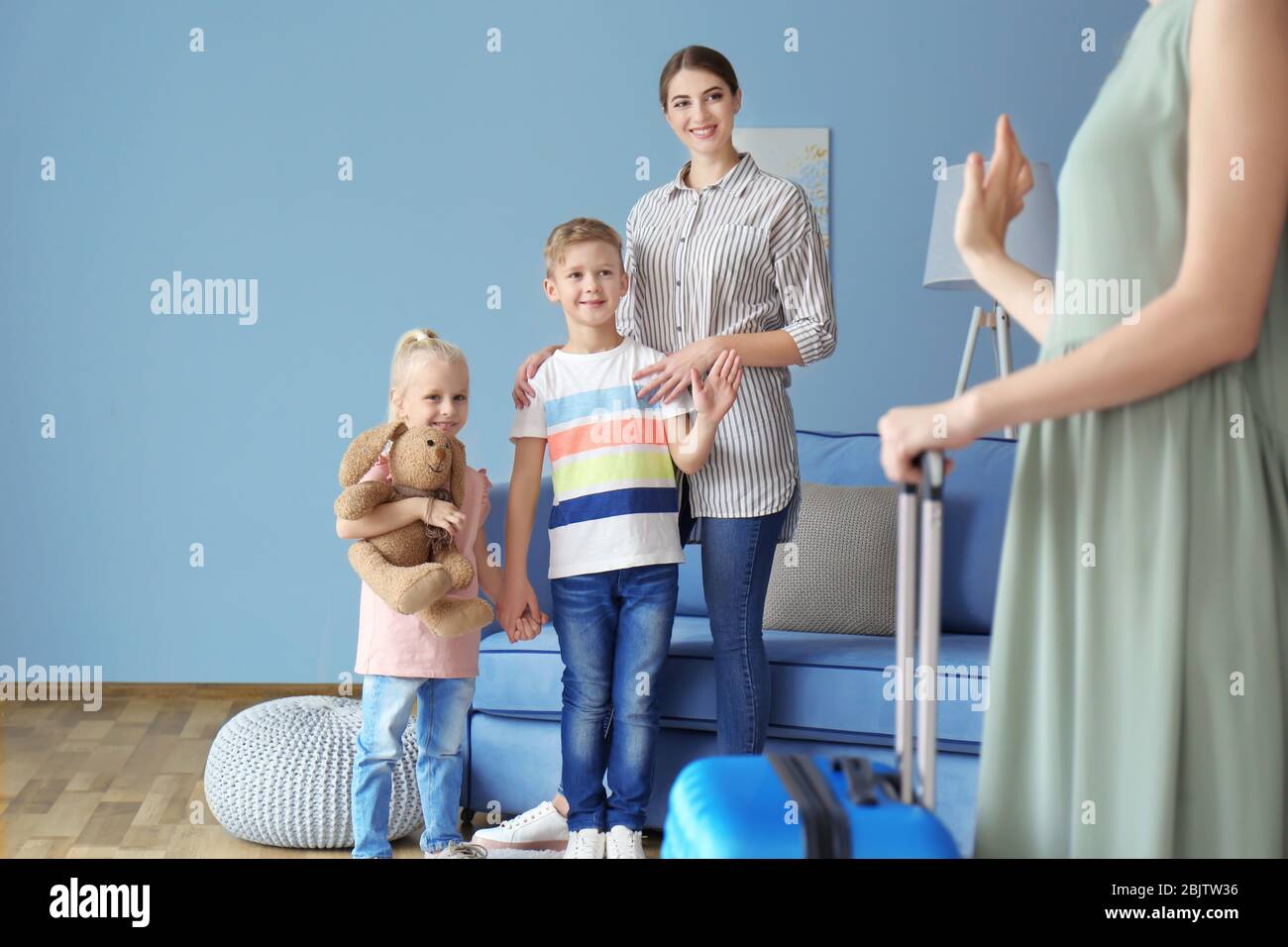 Mother leaving her children with nanny at home Stock Photo - Alamy