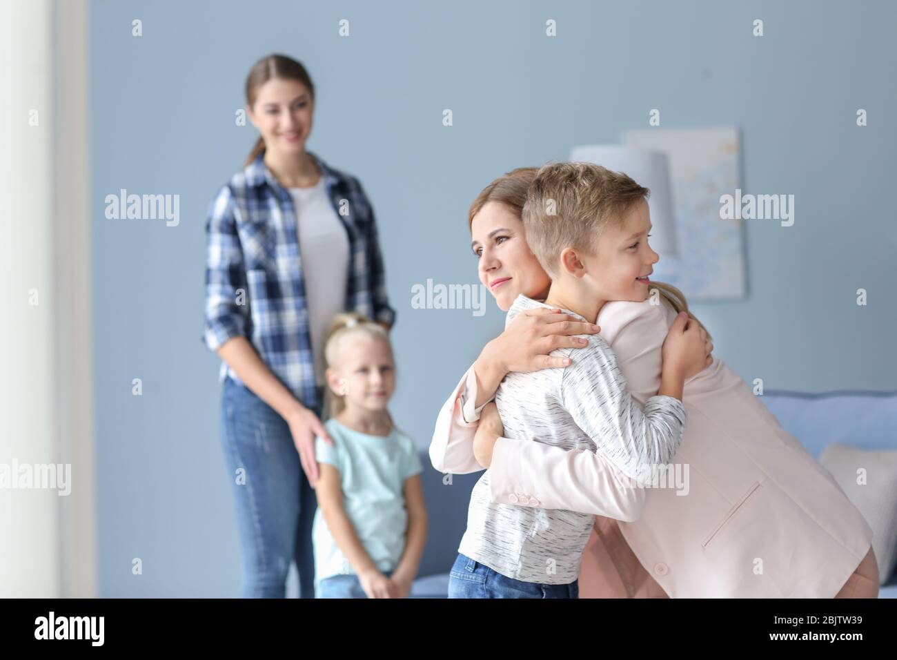 Mother leaving her children with nanny at home Stock Photo - Alamy