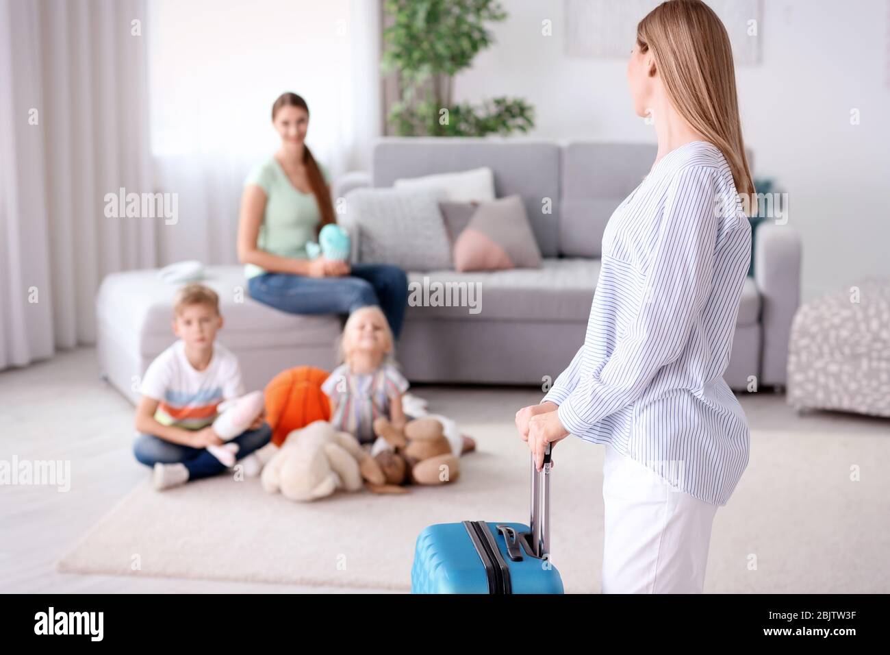 Mother leaving her children with nanny at home Stock Photo - Alamy