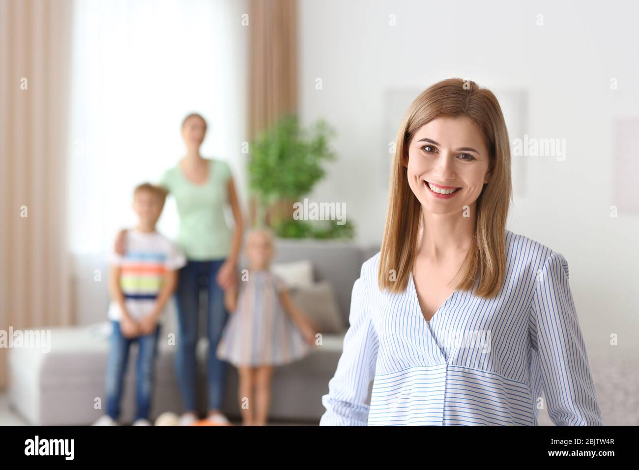 Mother leaving her children with nanny at home Stock Photo - Alamy