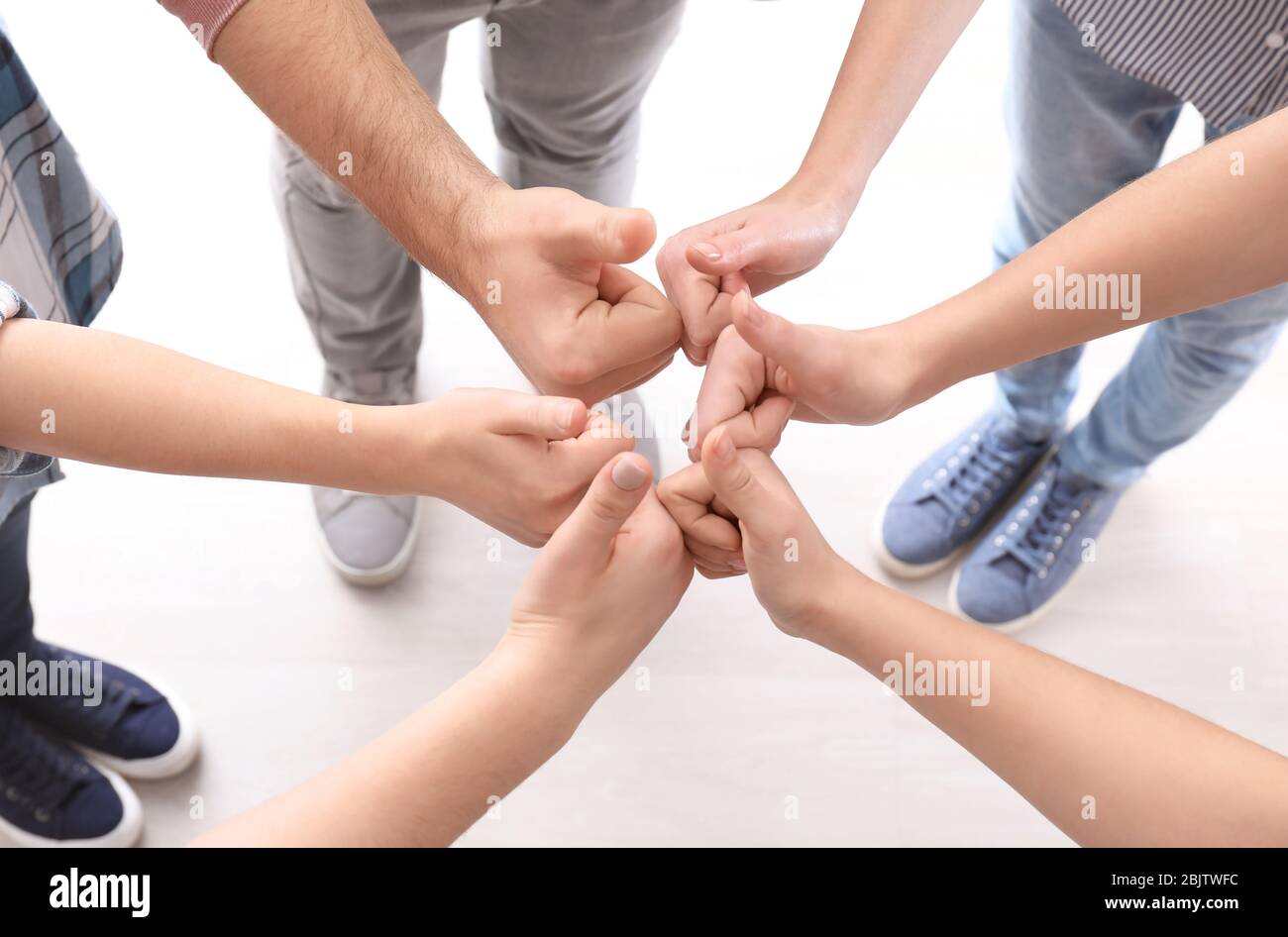 Young people standing in circle and showing thumb-up gesture as symbol ...