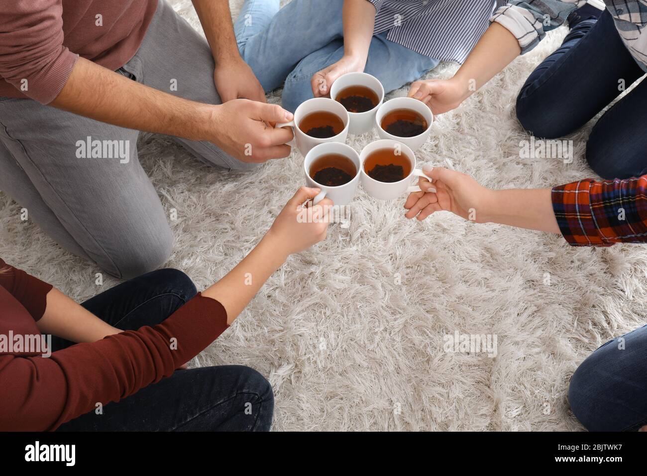 Group of people sitting on floor and drinking tea together. Unity ...