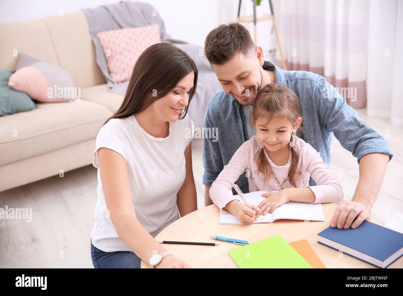 Cute little girl doing homework with parents Stock Photo - Alamy