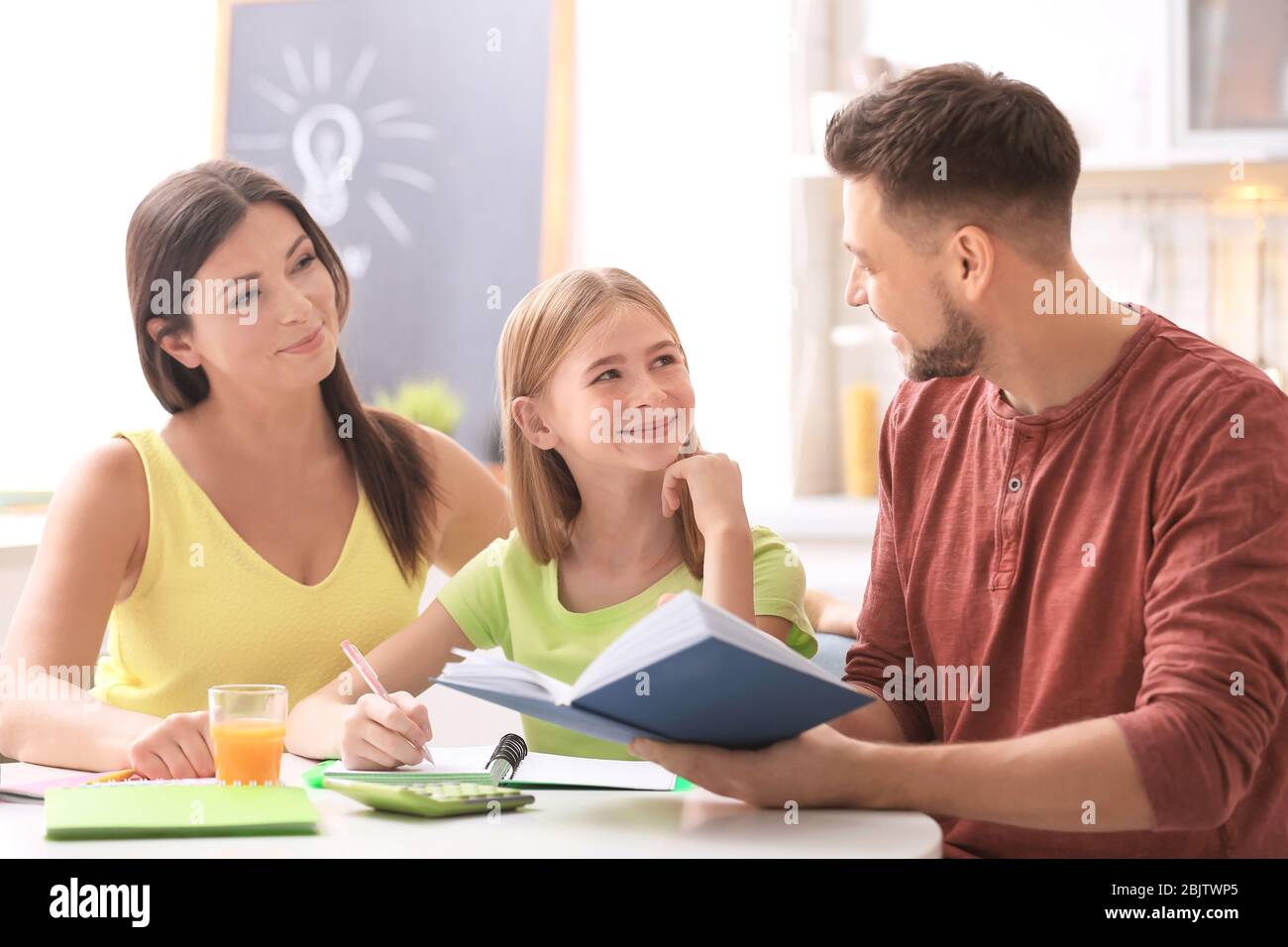Little girl doing homework with parents Stock Photo - Alamy