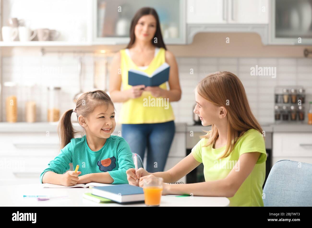 Cute little sisters doing homework in kitchen Stock Photo - Alamy