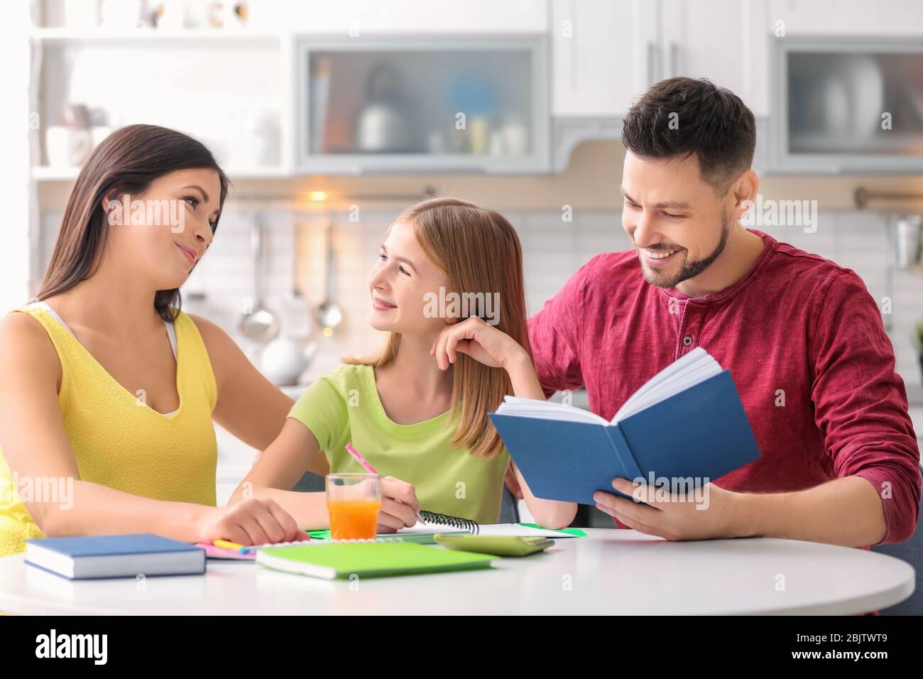 Little girl doing homework with parents Stock Photo - Alamy