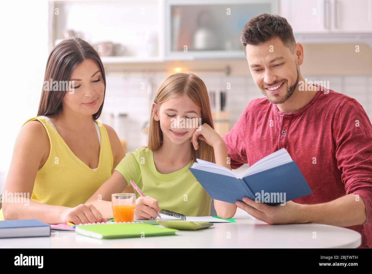 Little girl doing homework with parents Stock Photo - Alamy
